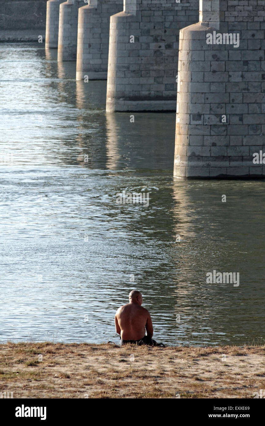 A sunbathing man sits down on the leaking coast Stock Photo - Alamy