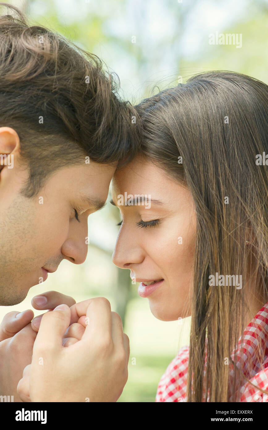 Couple touching foreheads and holding hands outdoors Stock Photo - Alamy