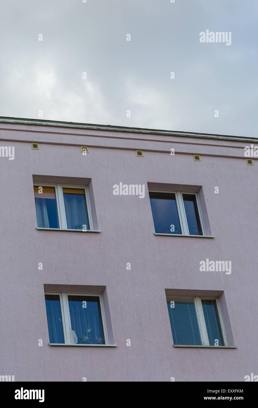 Close up of top part of block of flats building with blue sky ...