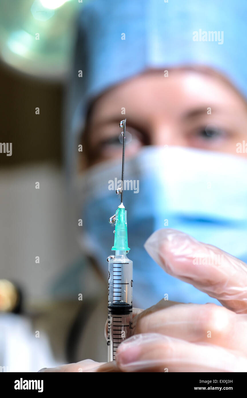 A nurse prepares her needle while wearing a mask and scrubs. Credit ...