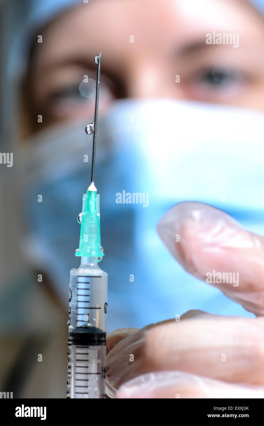 A nurse prepares her needle while wearing a mask and scrubs. Credit ...