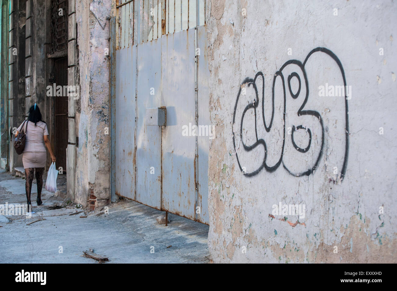 A woman walks past a mural of graffiti art with the word "Cuba" in ...