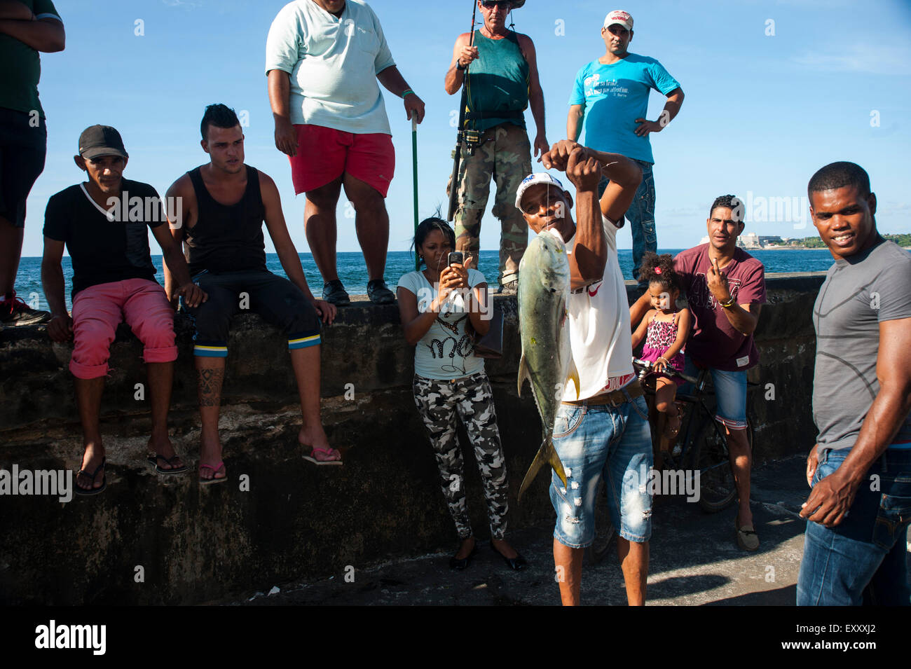 A crowd gathers around a man who caught a big fish off the Malecon in ...
