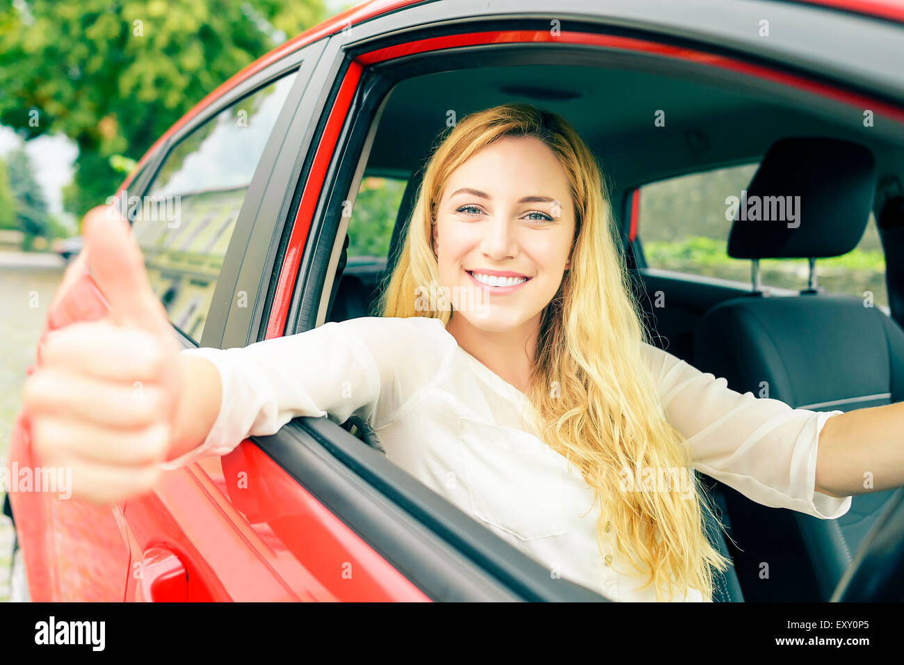 Happy smiling girl in a red car Stock Photo - Alamy