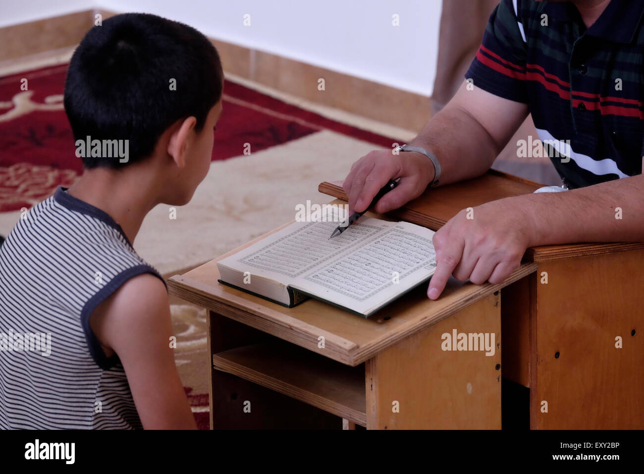 A young Muslim boy reading the Koran holy book during Islamic lecture ...