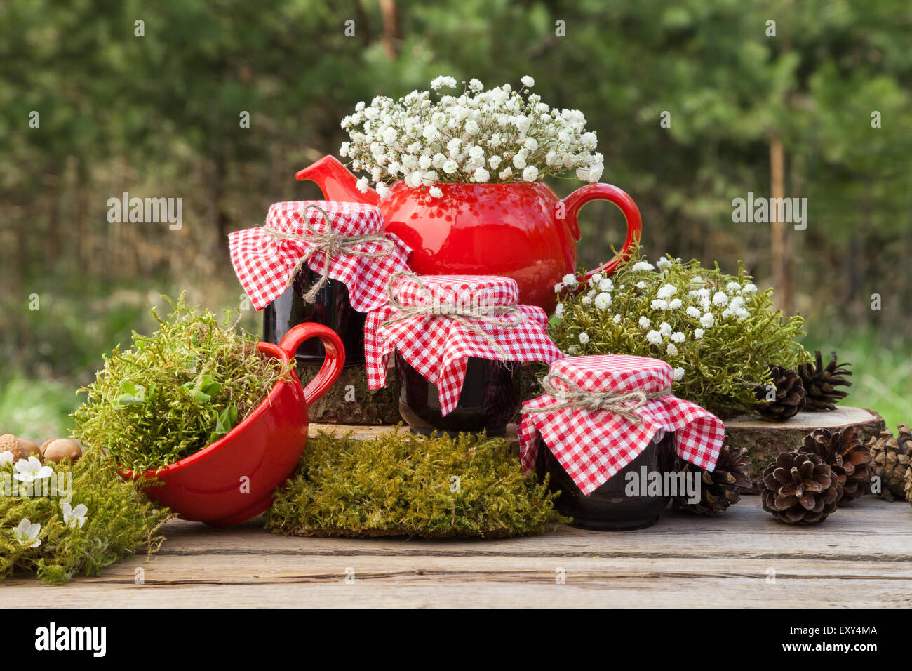 Red teapot, tea cup and three jars of healthy jam. Forest on background ...
