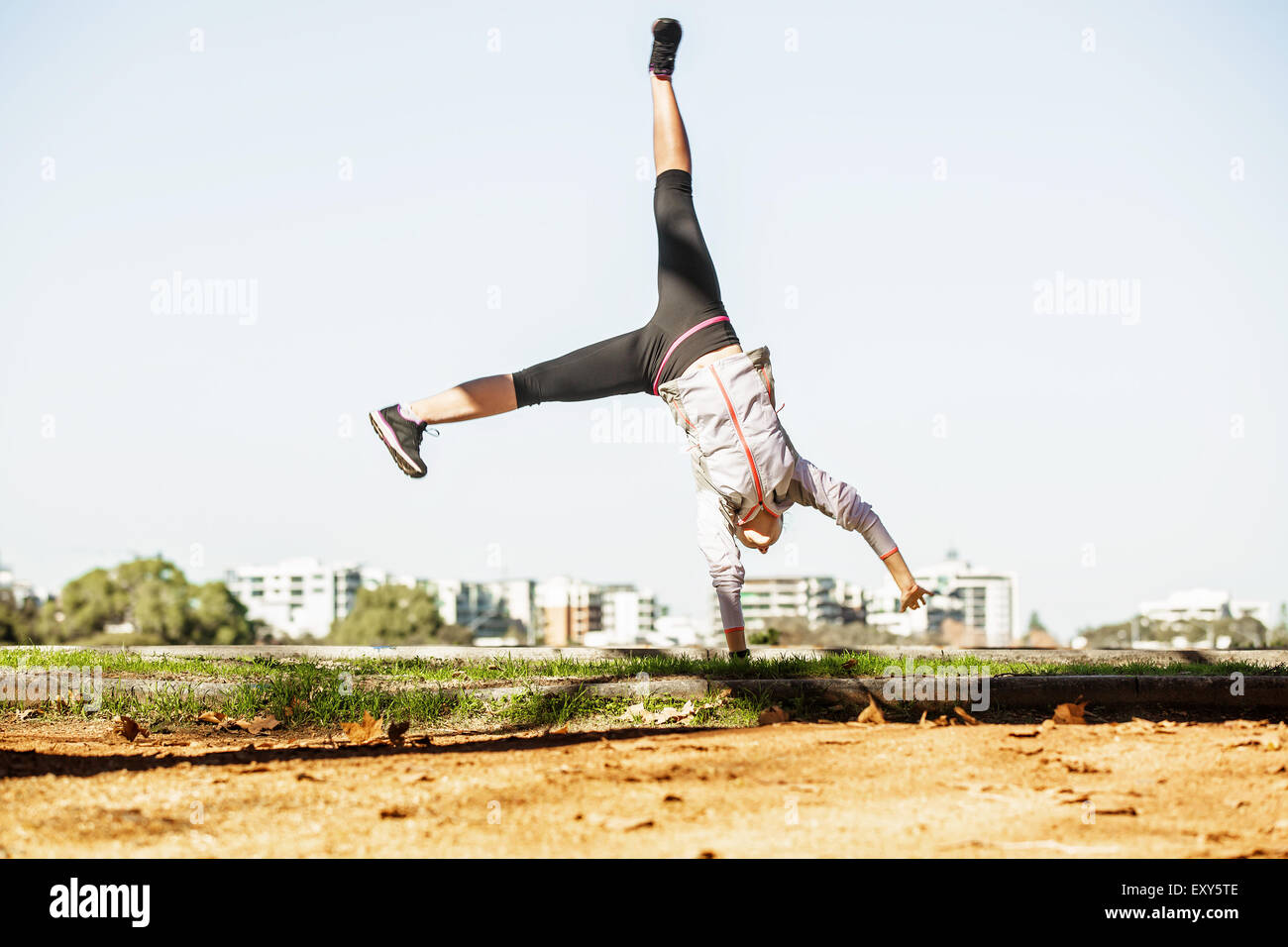 Young fit woman doing simple acrobatics exercise routine in autumn park ...