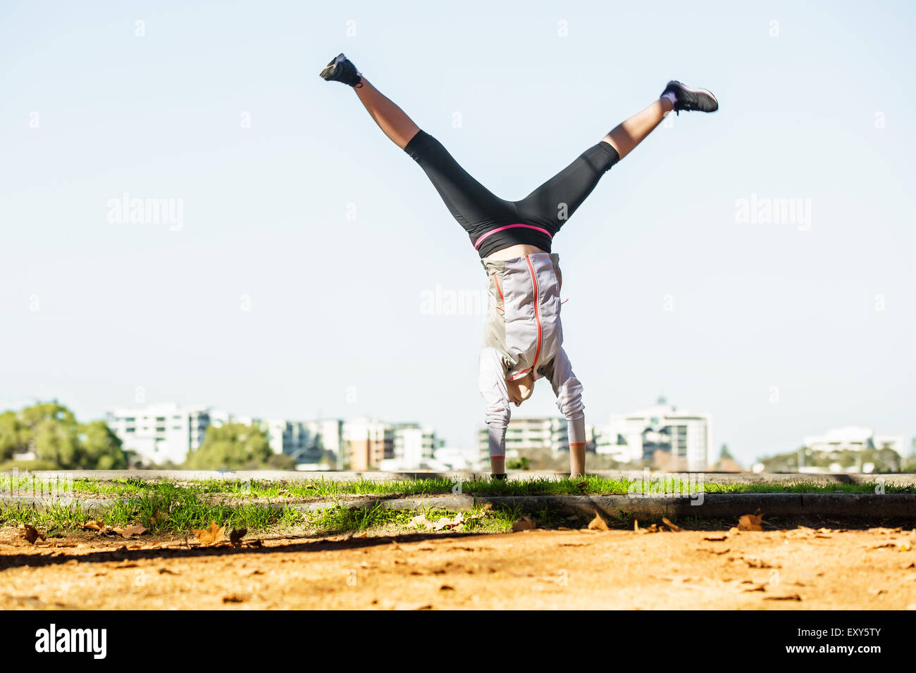 Young fit woman doing simple acrobatics exercise routine in autumn park ...