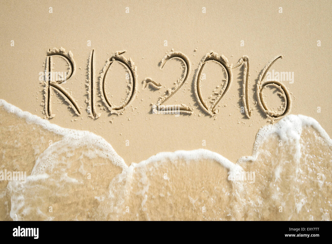 Simple Rio 2016 message handwritten in clean numbers on smooth sand ...
