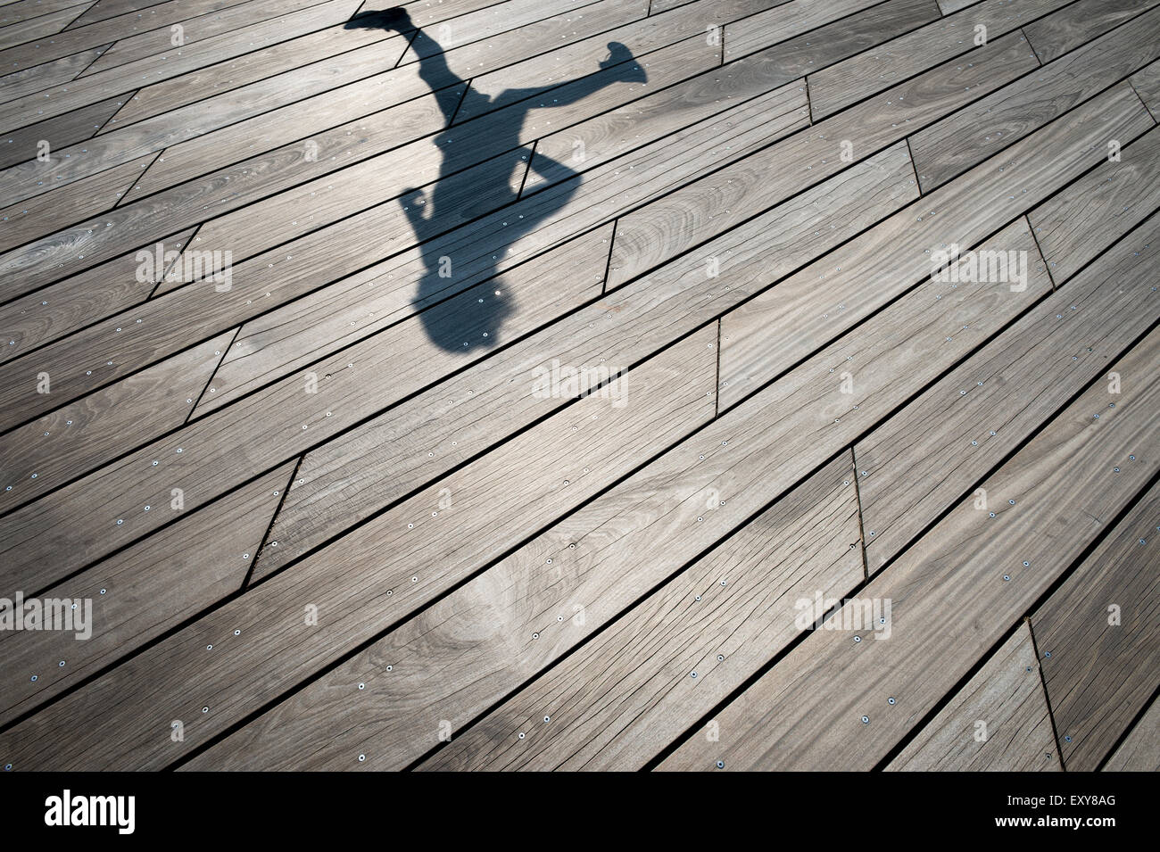 Shadow of runner jogging across weathered smooth wood plank boardwalk ...