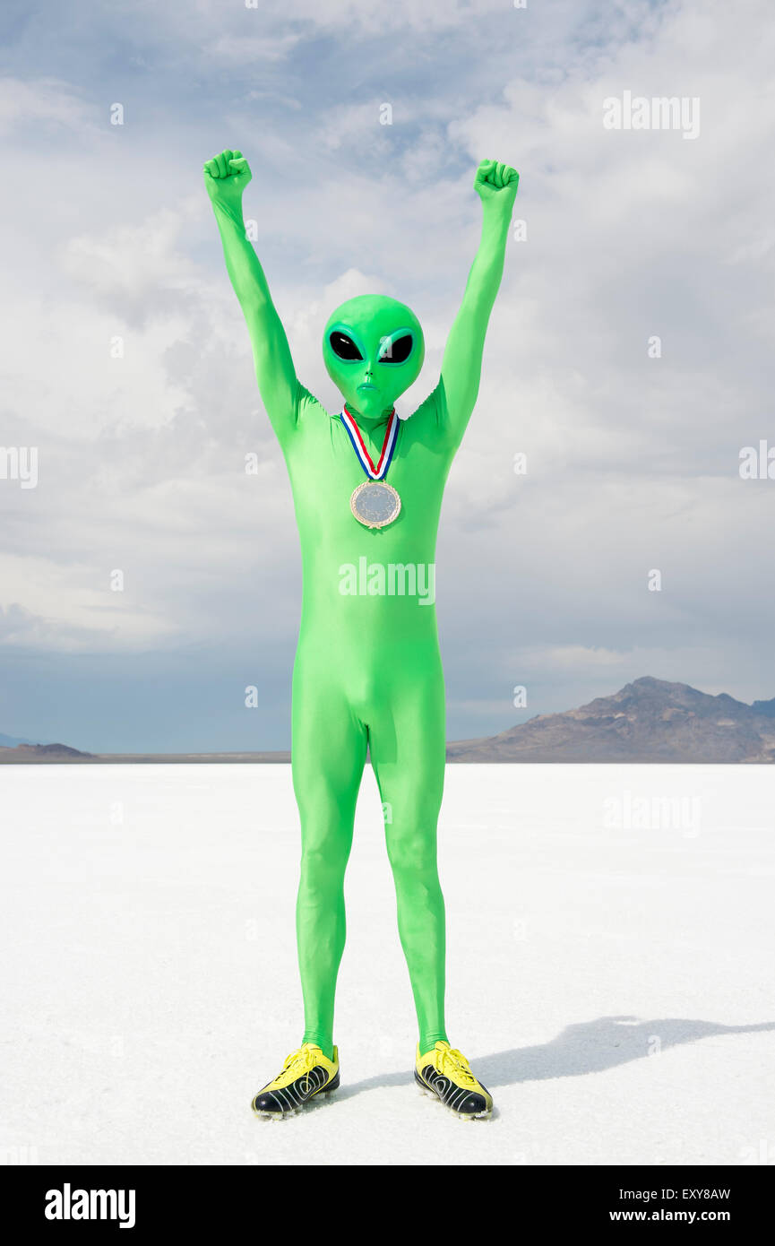 Green alien athlete wearing gold medal standing with arms raised on ...