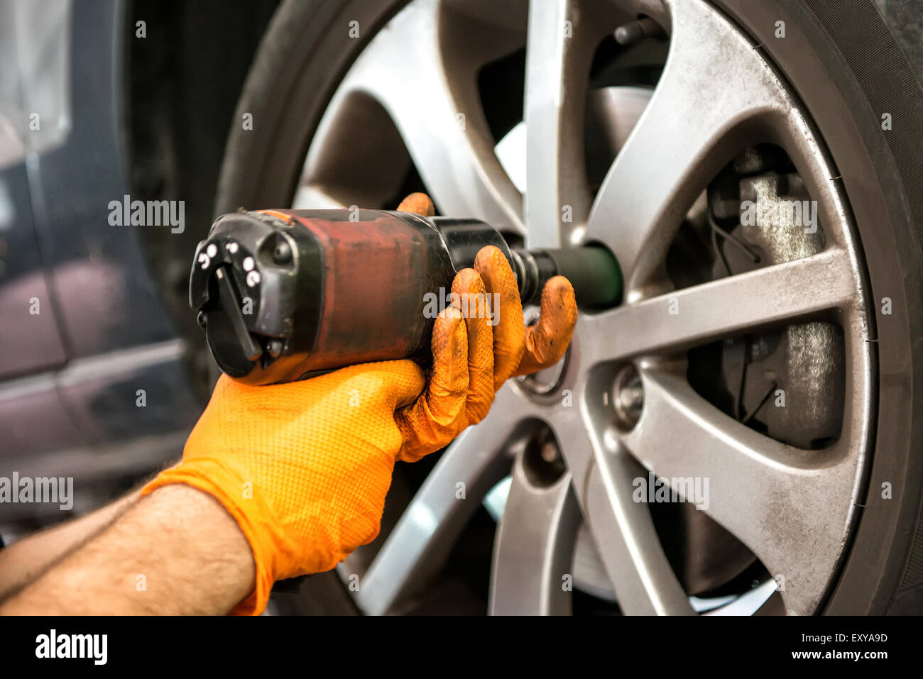 Mechanic working on a car wheel tightening or loosening the bolts on ...