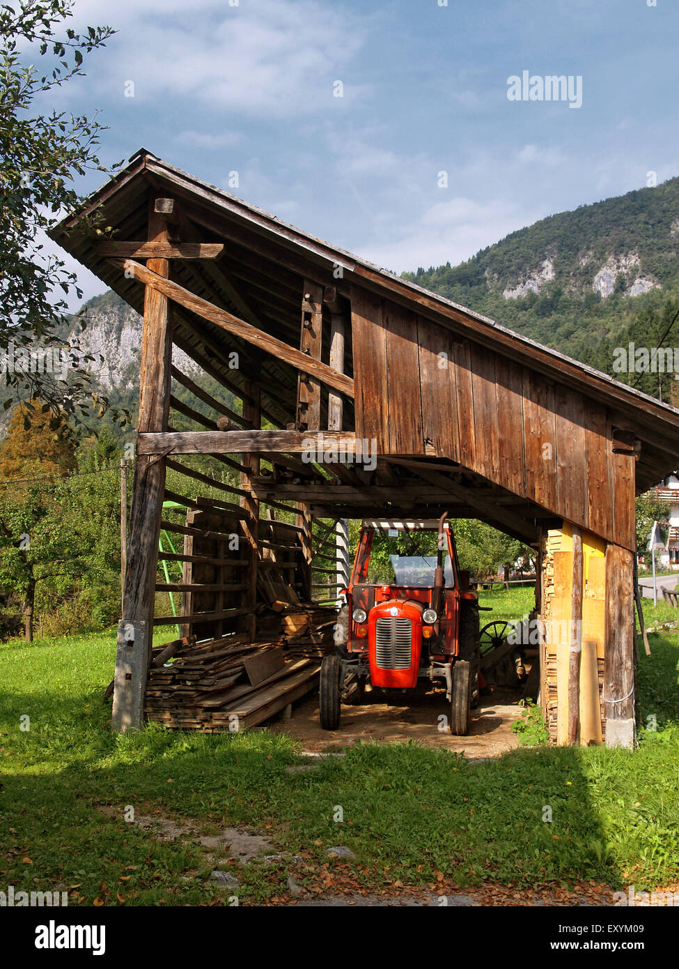 Vertical view of a kozolec hayrack with a red farm tractor parked in ...