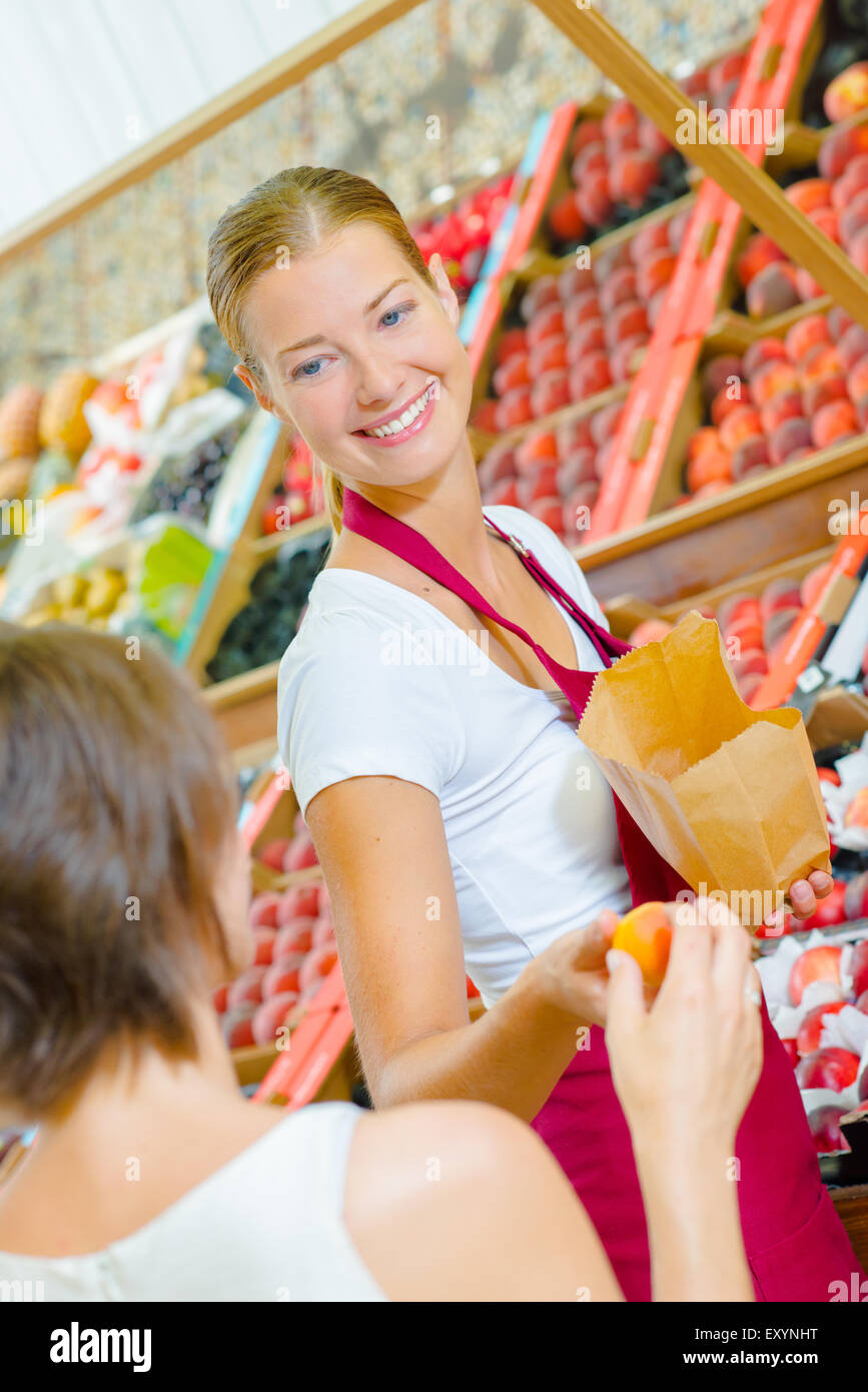 Shop assistant passing orange Stock Photo - Alamy