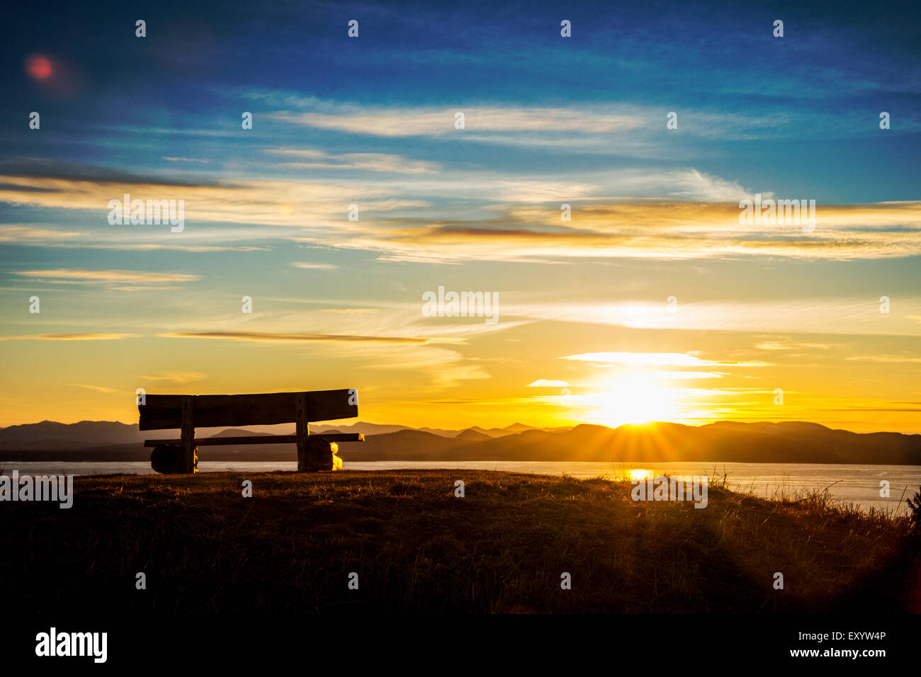 A bench overlooking a sunset on a hill overlooking Lake Champlain Stock ...