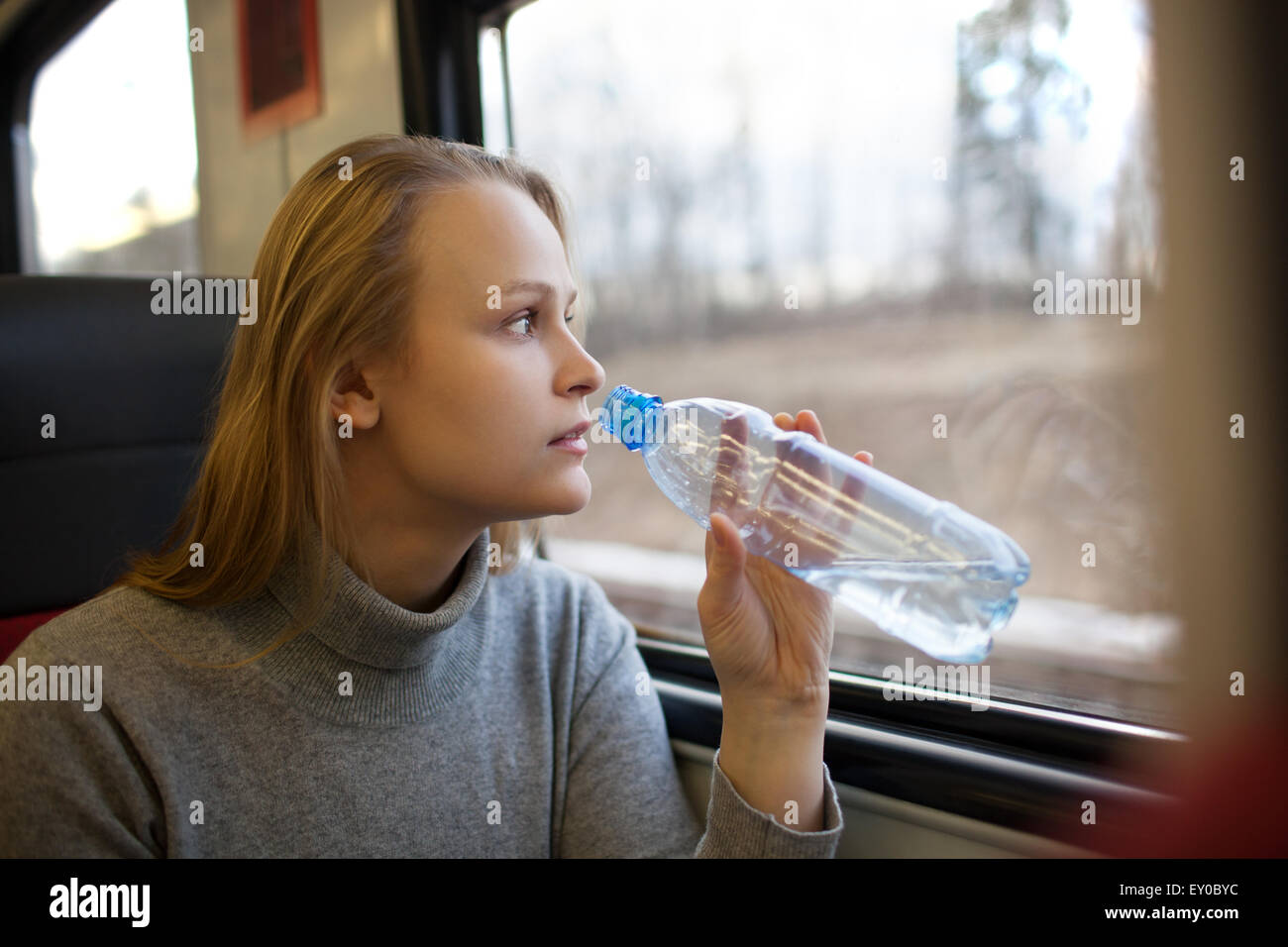 Woman drinking water and looking out train window Stock Photo - Alamy