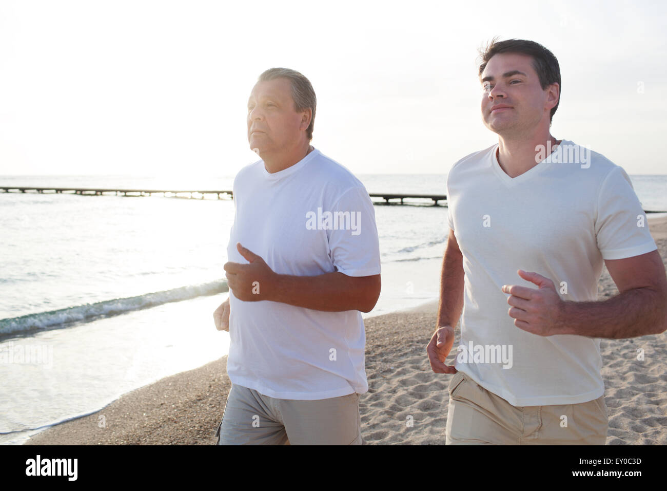 Two men running along the coast in bright sunlight Stock Photo - Alamy