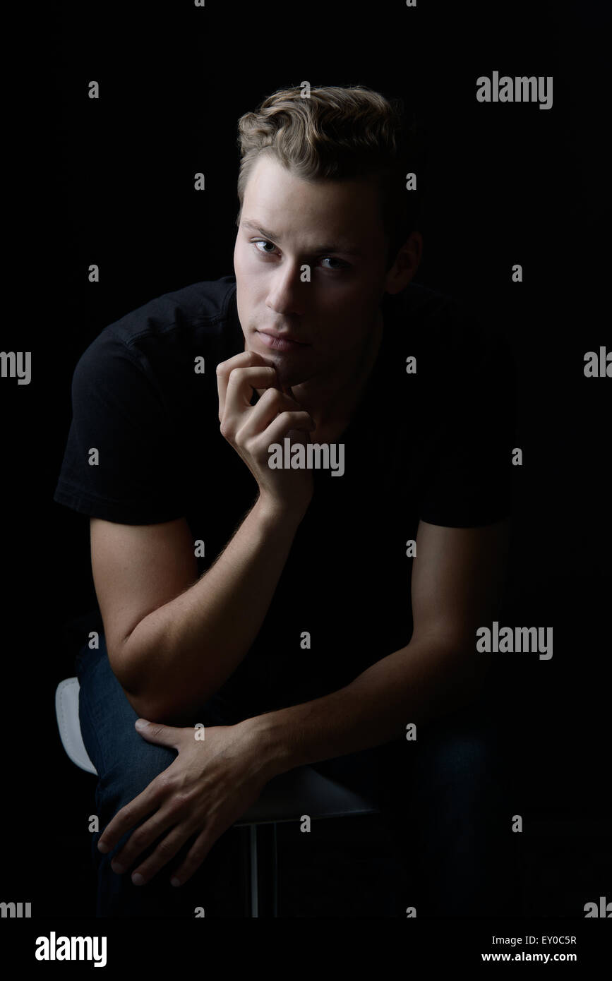 A blond, Caucasian man, sitting and leaning forward. He appears to be ...