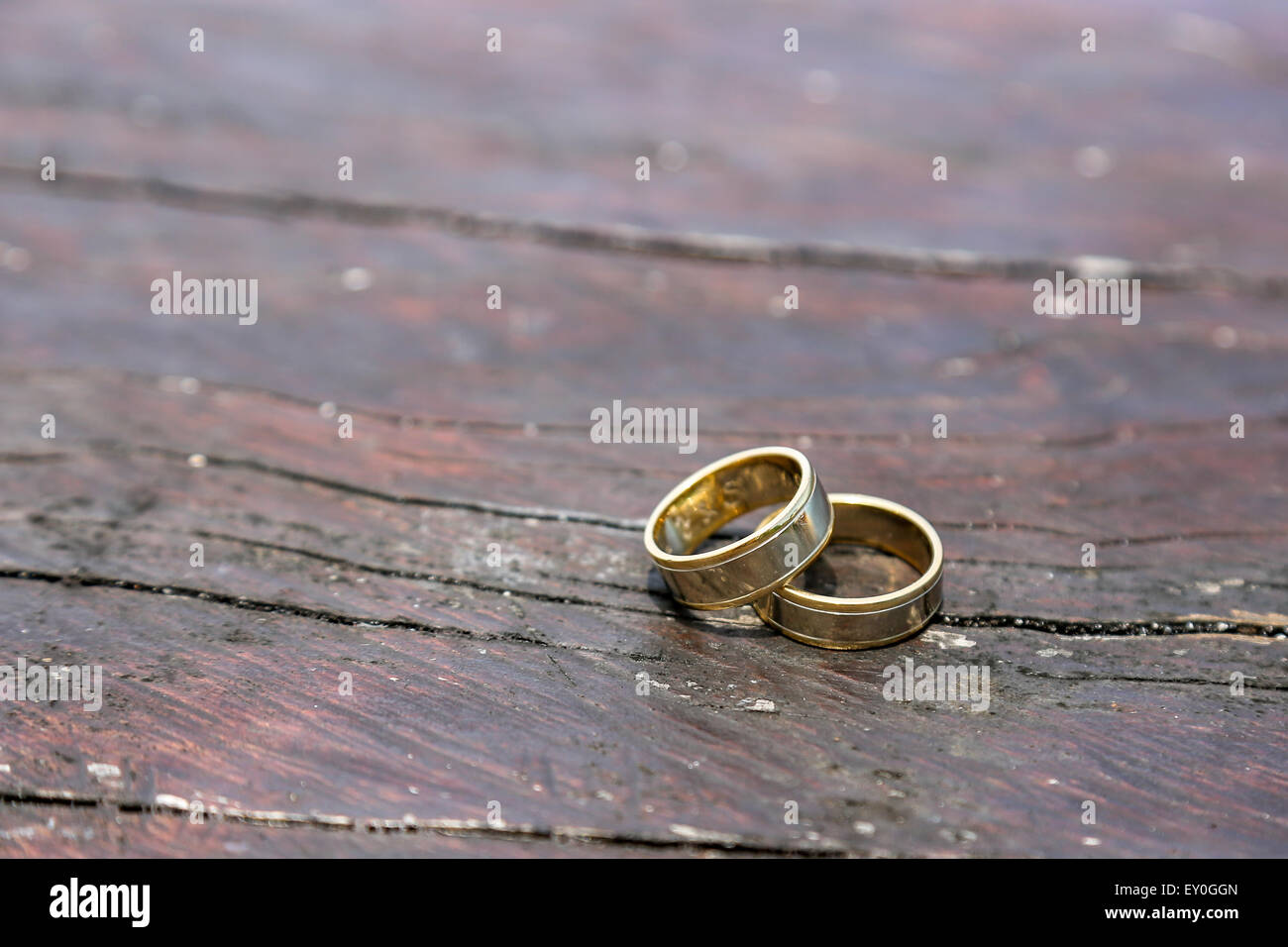 two medium size gold wedding rings placed on top of each other on the ...