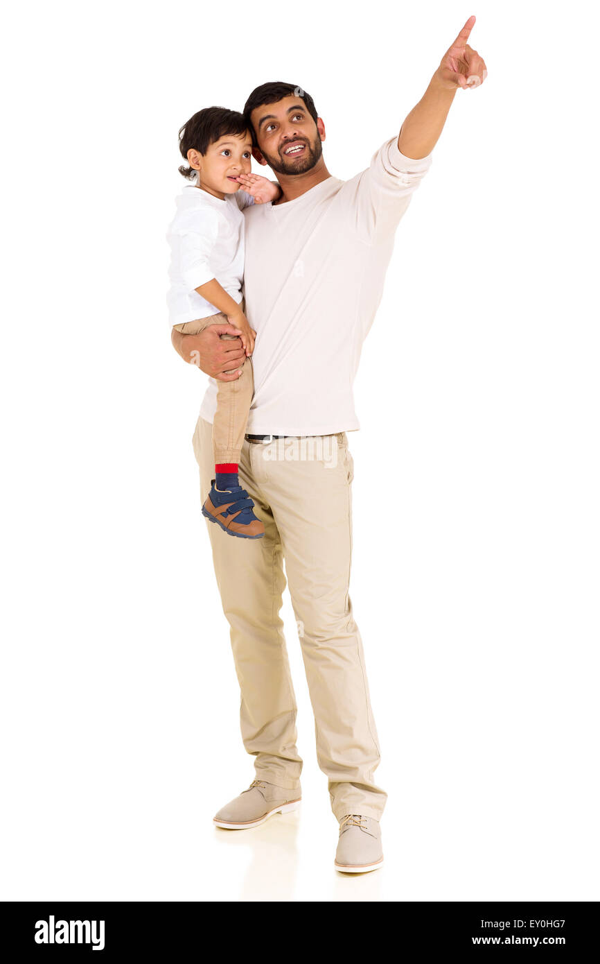 young Indian father and son pointing at empty space on white background ...