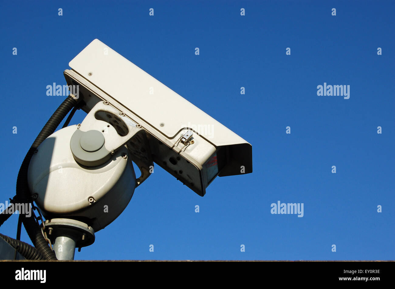 A closed circuit security camera photographed against a clear blue sky ...