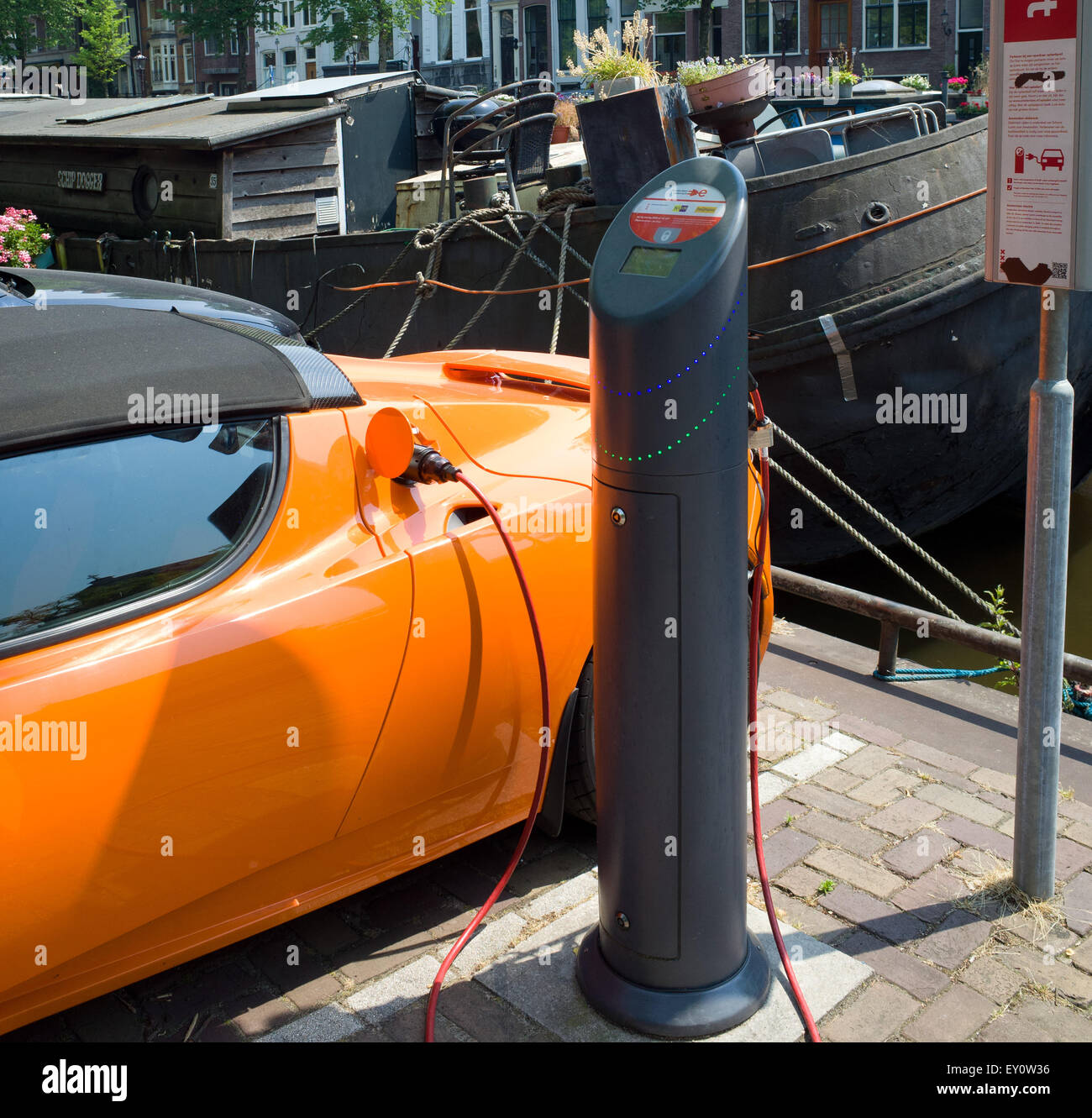 Bright Orange Tesla electric car charging at public charging station ...