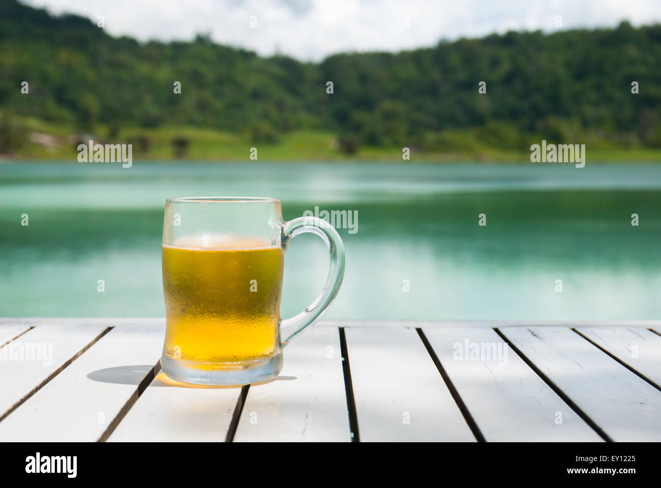 A glass of cold beer on table at a cafe on the side of Lake Linow, a ...