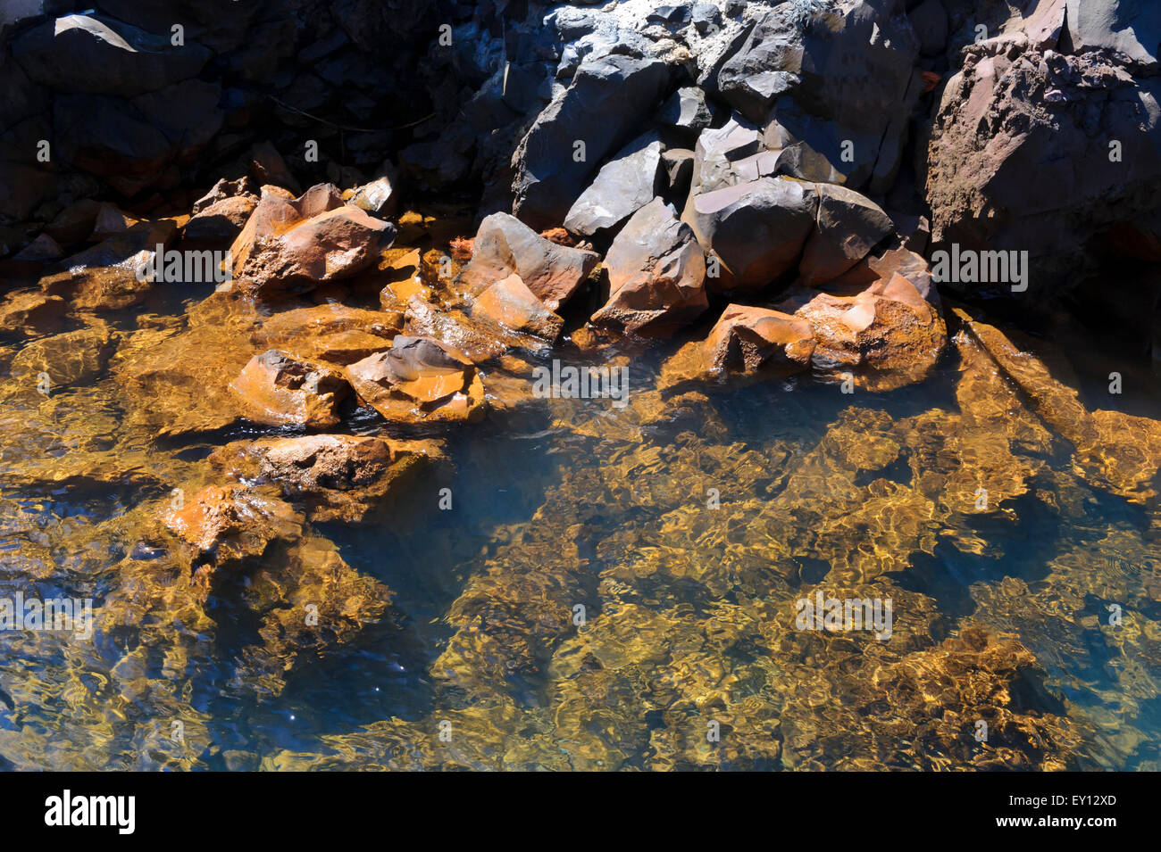 Rusty colour of rocks in the sea water near the Volcanic island ...