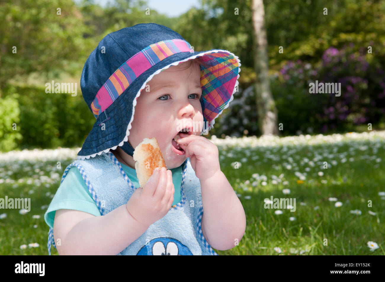 Little girl wearing a sun hat outdoors eating bread Stock Photo - Alamy