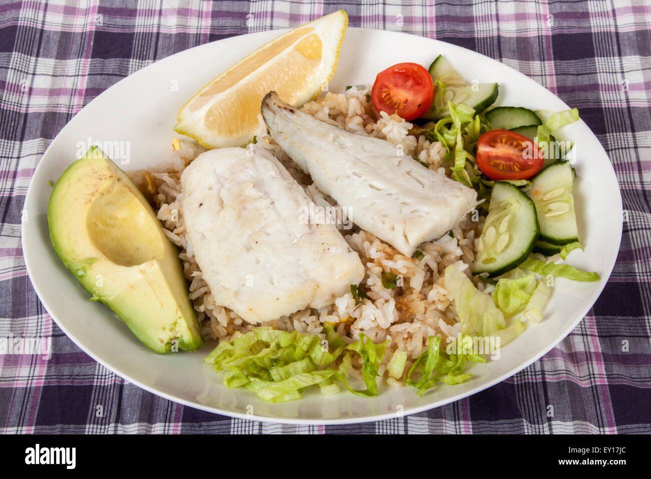 Studio shot of hake fish on fried jasmine rice with lemon, avocado and ...