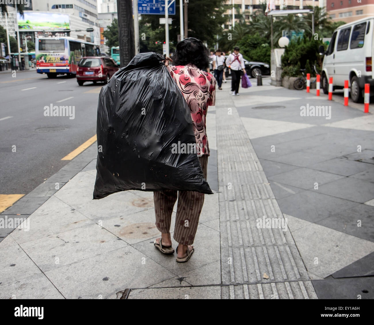 senior pulls a plastic bag on her back on the streets of Shenzhen Stock ...