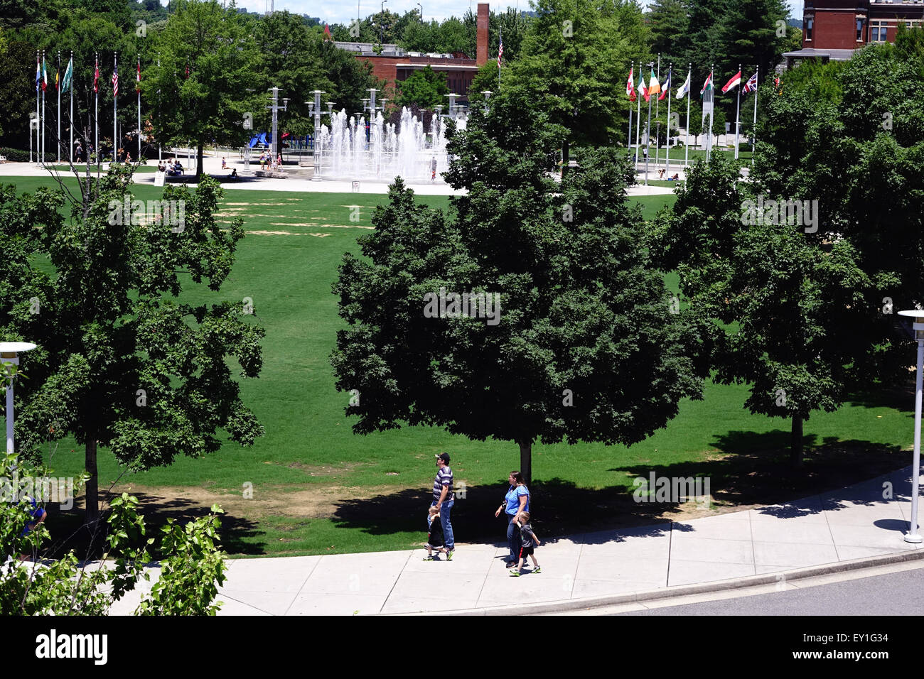 A man and woman walk with children on a paved path in Worlds Fair park ...