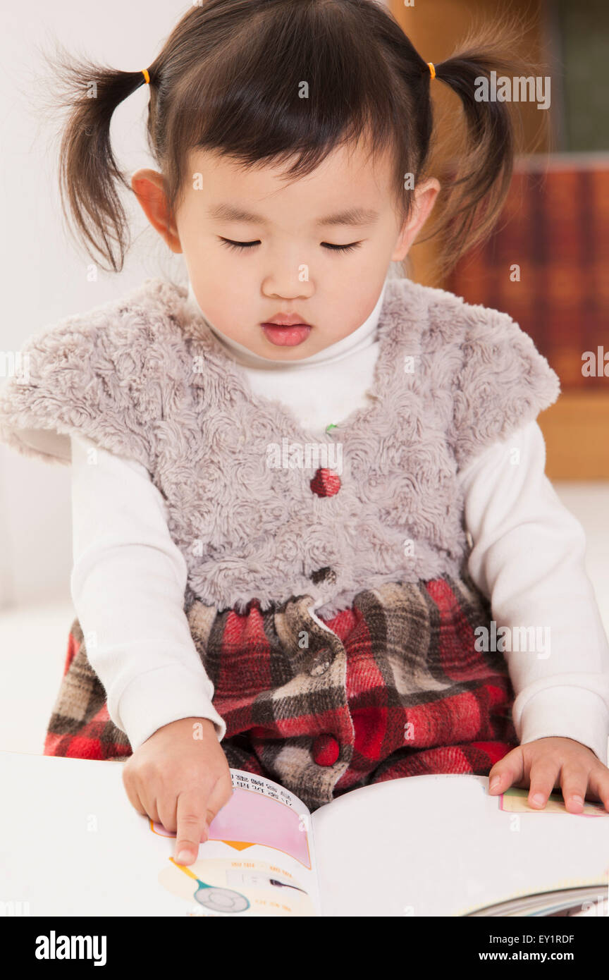 Little girl pointing and reading a book Stock Photo - Alamy