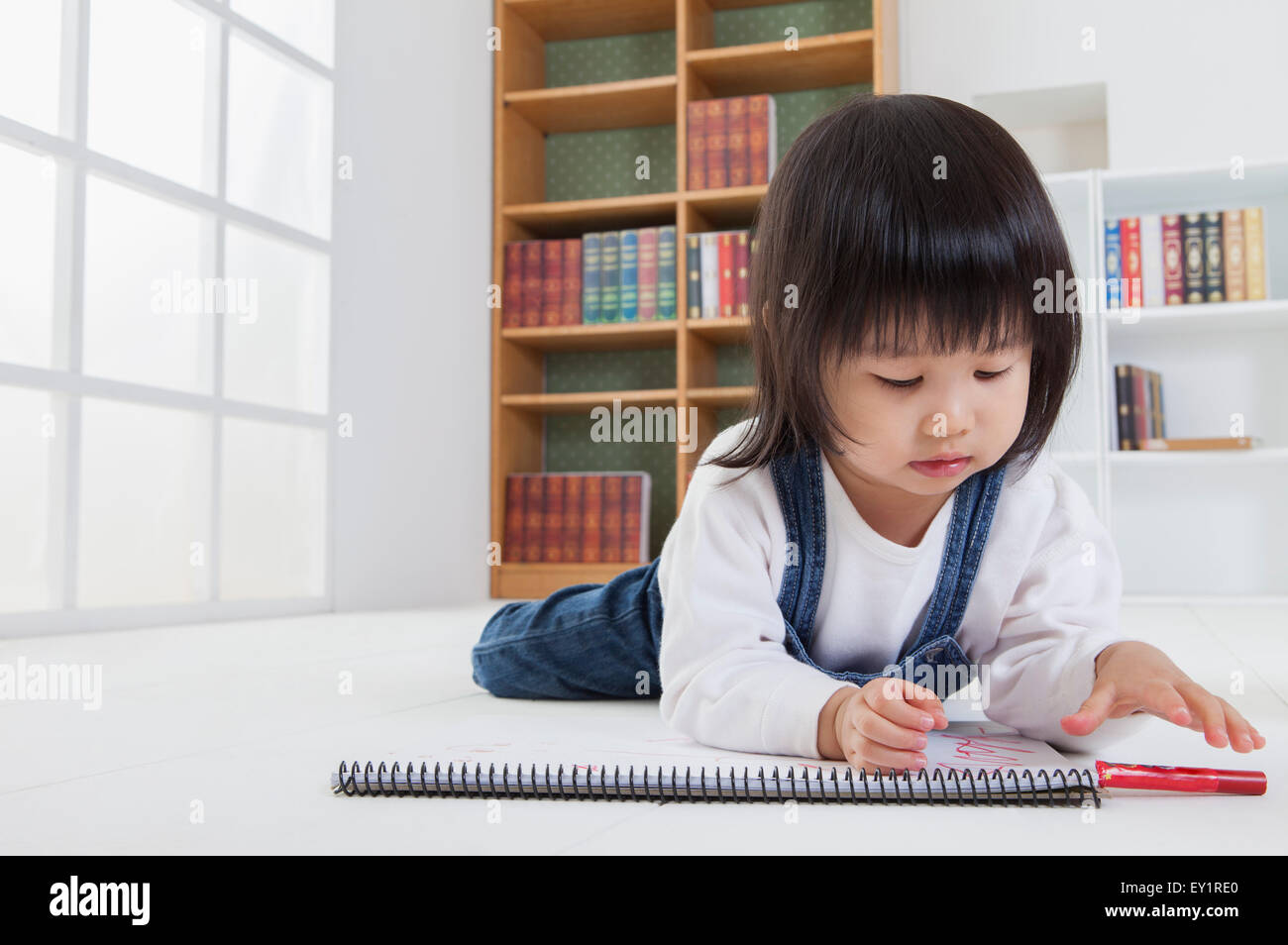 Little girl holding crayon and drawing Stock Photo - Alamy