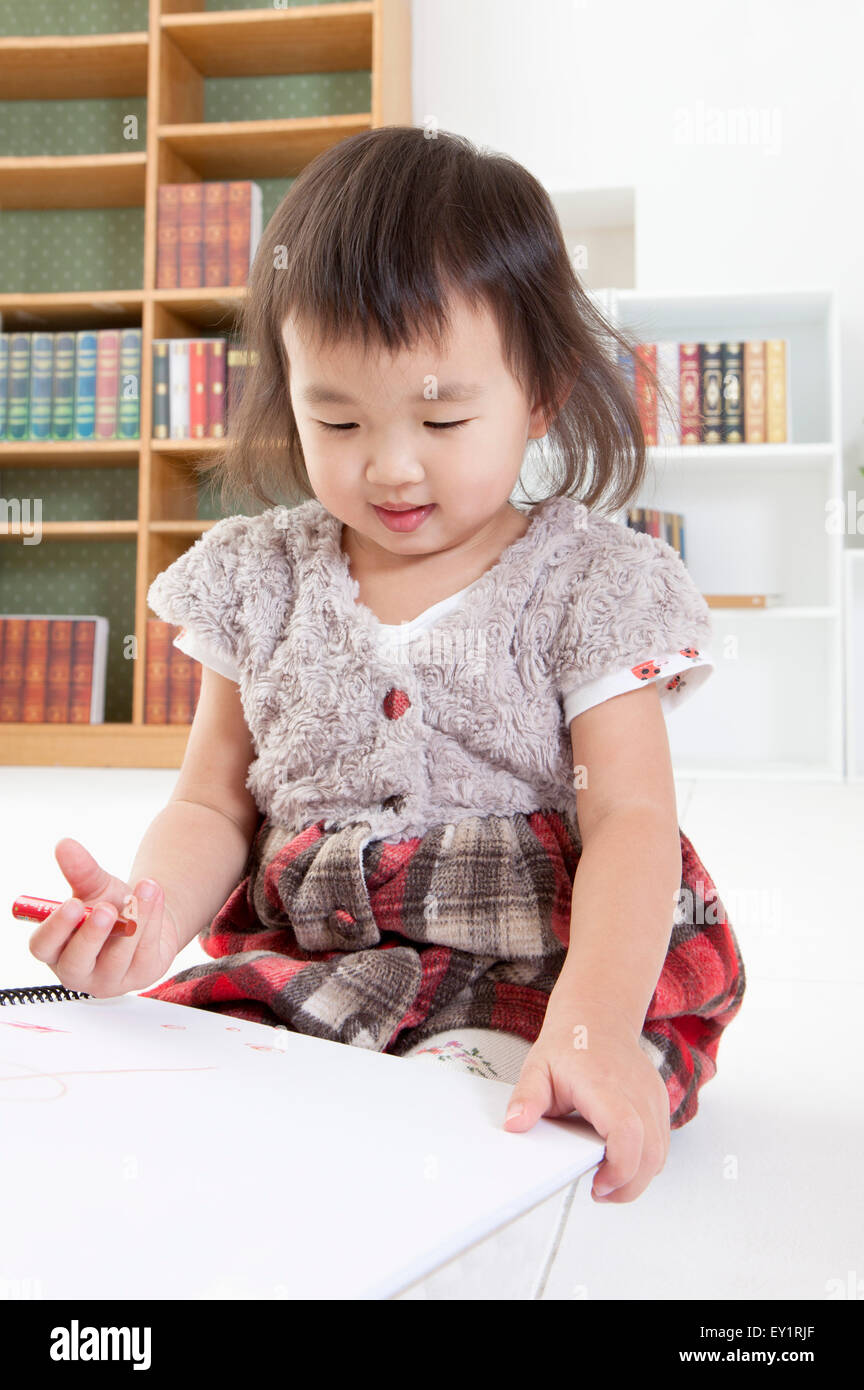 Little girl holding crayon and looking down Stock Photo - Alamy