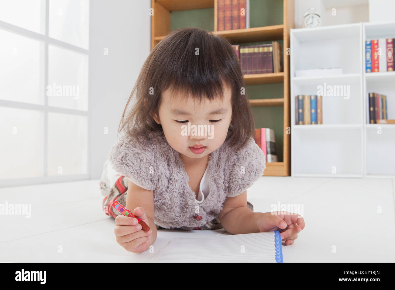 Little girl holding crayon and looking down Stock Photo - Alamy
