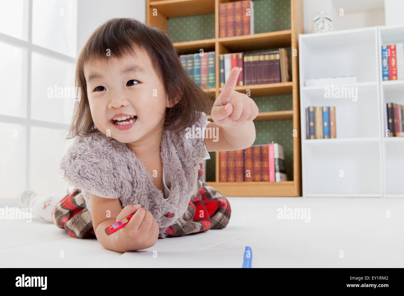 Little girl holding crayon and looking away with smile Stock Photo - Alamy
