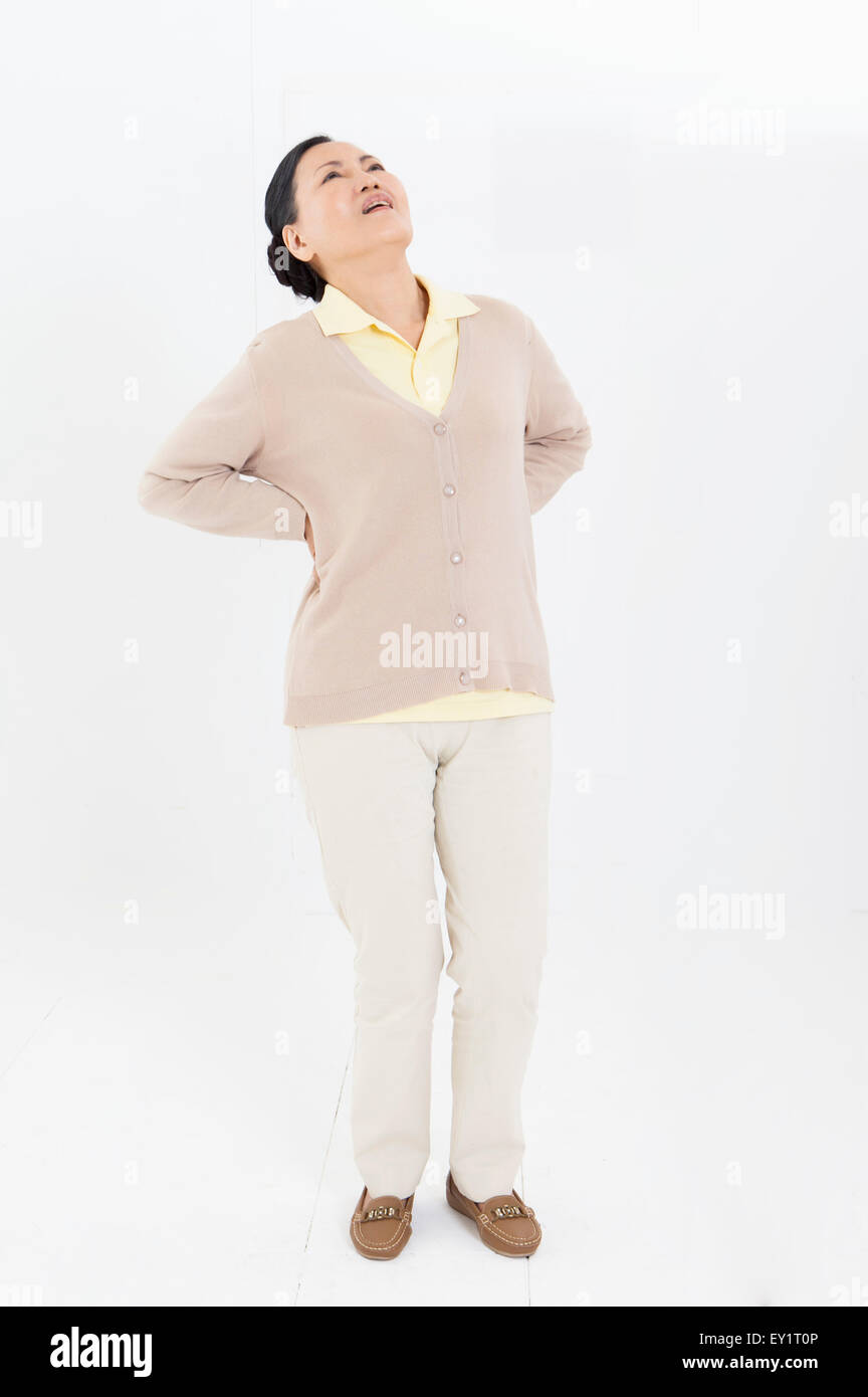 Senior woman standing with hands on back Stock Photo - Alamy