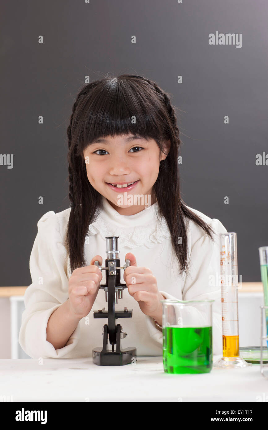 Girl using microscope and smiling at the camera Stock Photo - Alamy