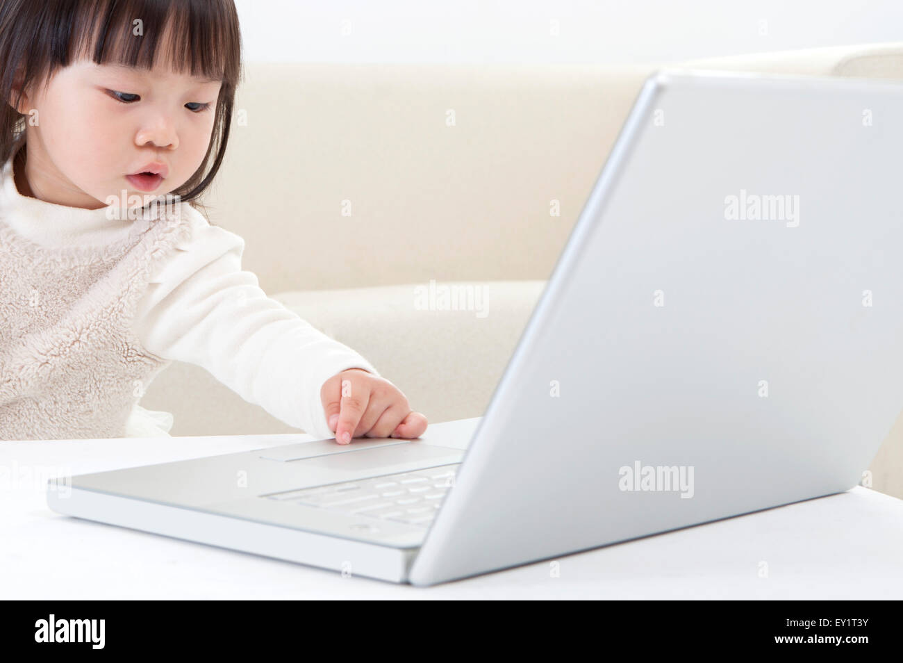 Baby girl touching laptop and looking down Stock Photo - Alamy