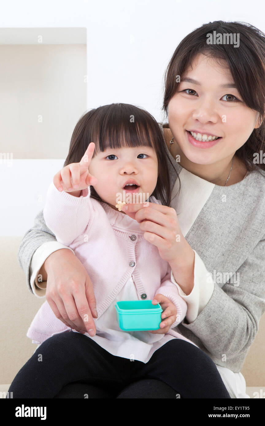 Baby girl sitting and eating cookies with smile Stock Photo - Alamy