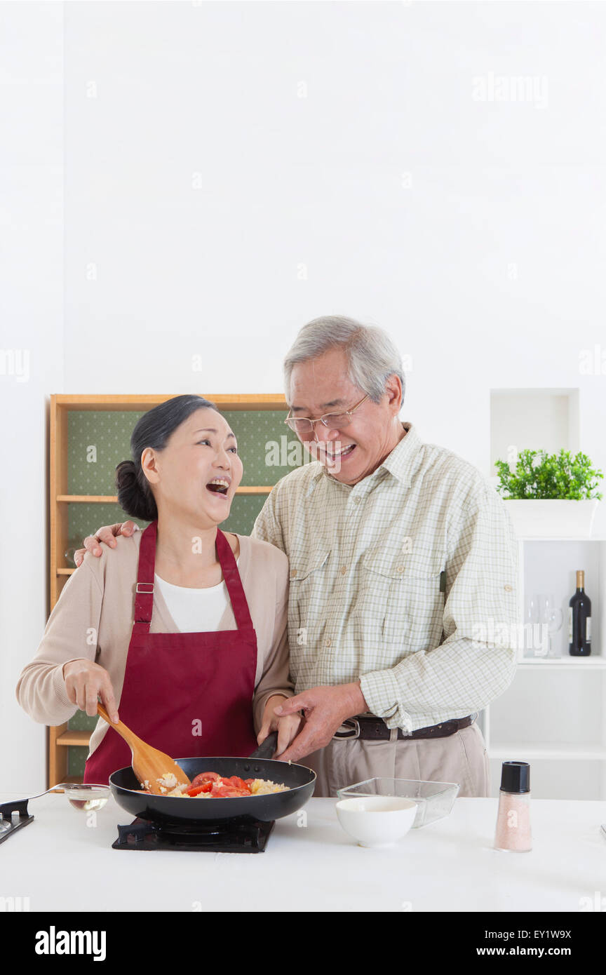 Senior couple cooking in the kitchen and smiling happily Stock Photo ...
