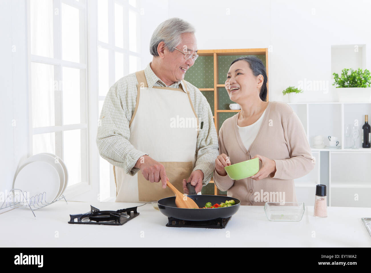 Senior couple cooking in the kitchen and smiling happily Stock Photo ...