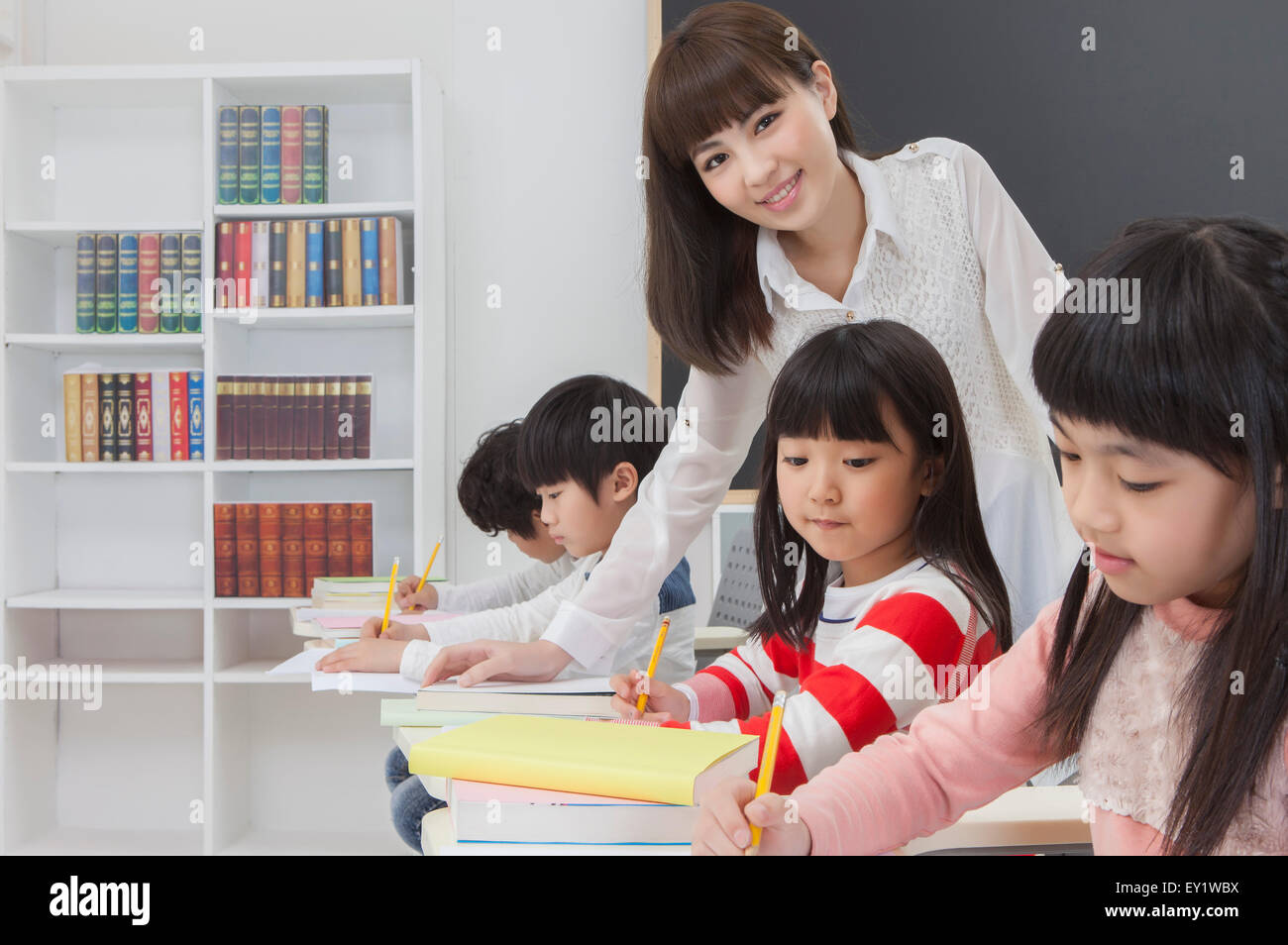 Young teacher teaching students in the classroom and smiling Stock ...
