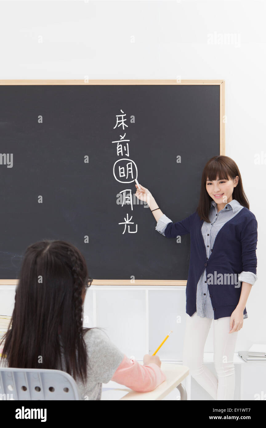 Young teacher teaching and pointing at the blackboard with smile Stock ...