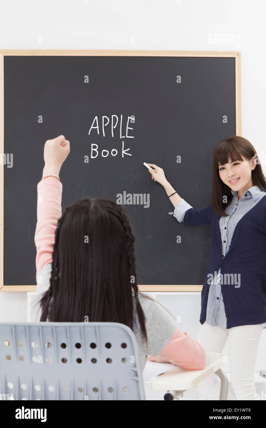 Young teacher teaching and pointing at the blackboard with smile Stock ...