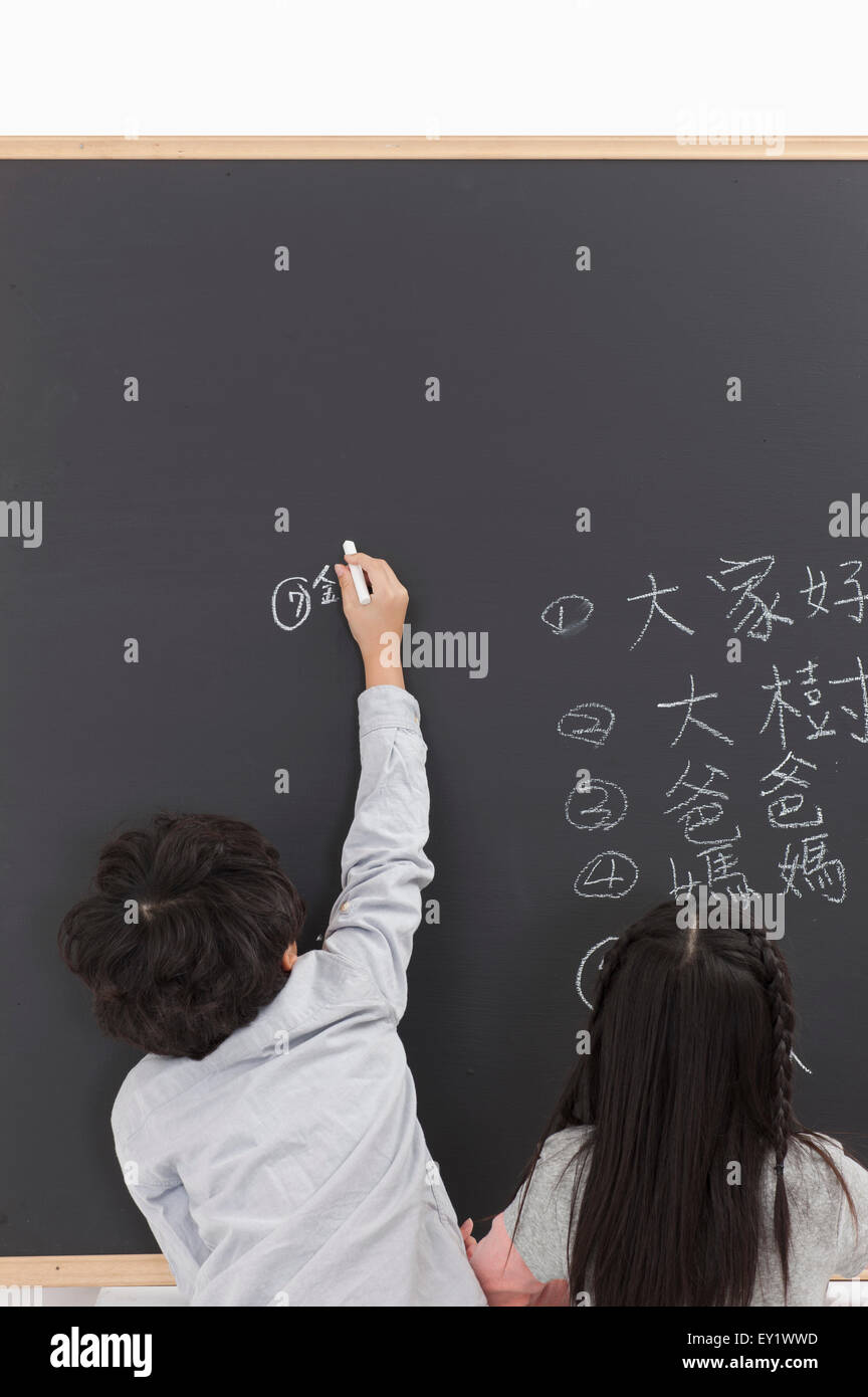 Children writing on the blackboard in the classroom Stock Photo - Alamy