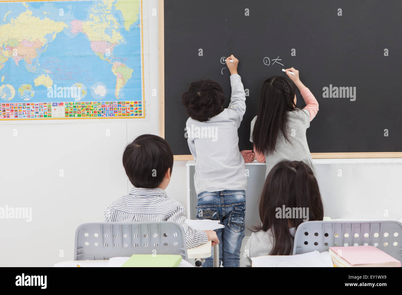 Children writing on the blackboard in the classroom Stock Photo - Alamy
