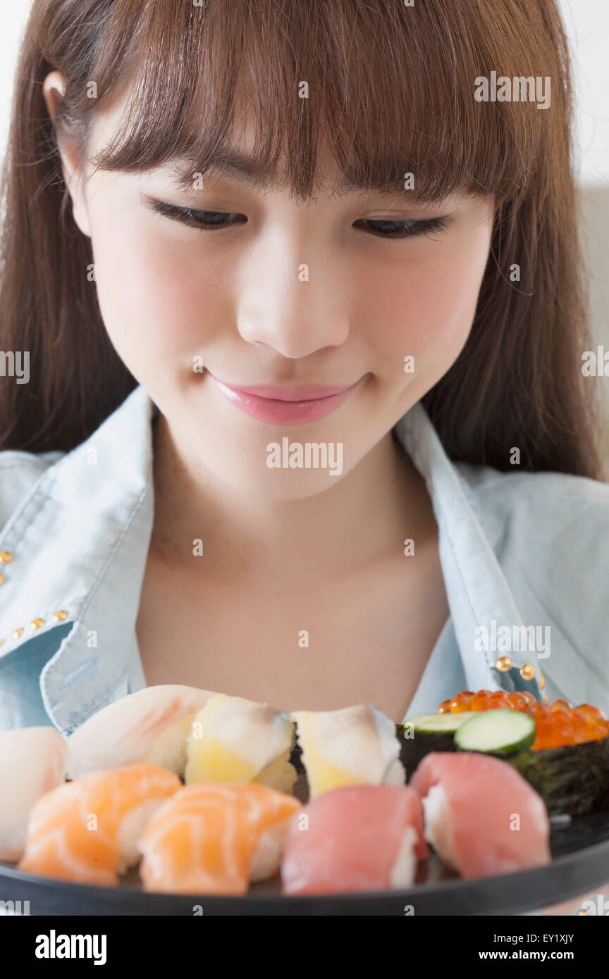 Young woman looking at sushi with smile Stock Photo - Alamy