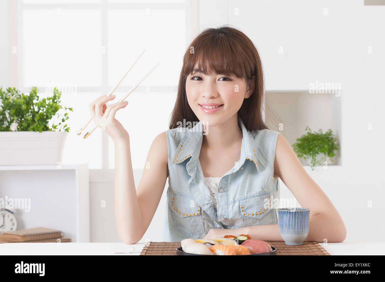 Young woman holding chopsticks and smiling at the camera Stock Photo ...